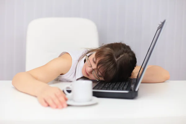 Young woman comically sleeps on laptop at office - Stock Image - Everypixel